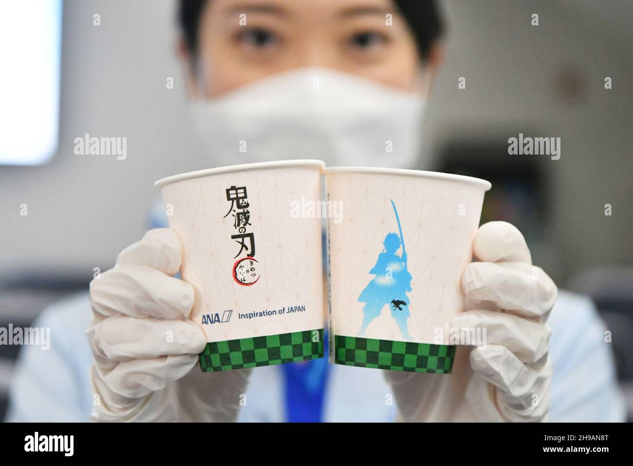 An ANA flight attendant introduces paper cups of "Demon Slayer (Kimetsu ...