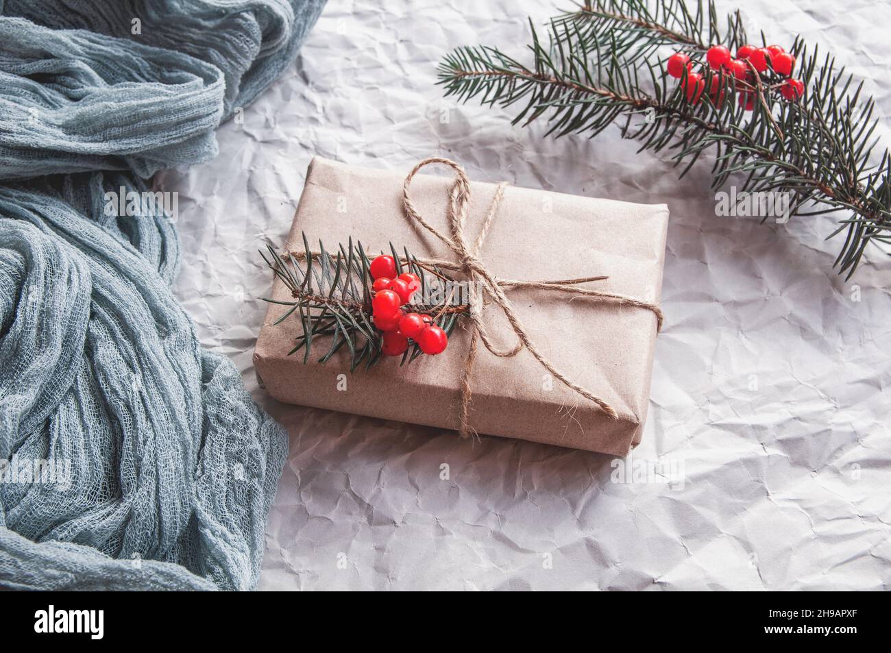 Gift box next to vintage Gauze gray and spruce leaves red berries ...
