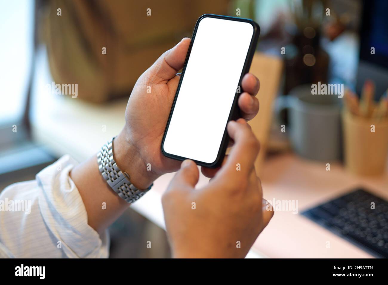 Businessman holding smartphone, using smartphone at his office desk ...