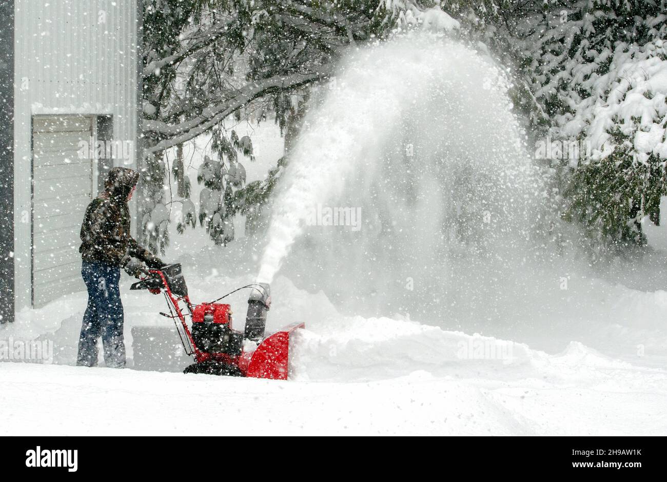 A man uses a snow blower to make a path through deep snow to the pole ...