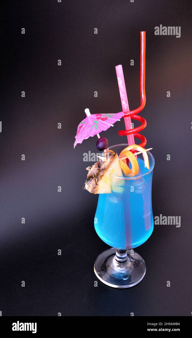 Blue lagoon cocktail, beach drink in a tall glass with straws and an ...