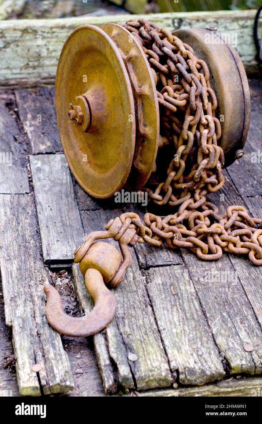 An iron spool holds rusty chain with a large iron hook on the end Stock ...