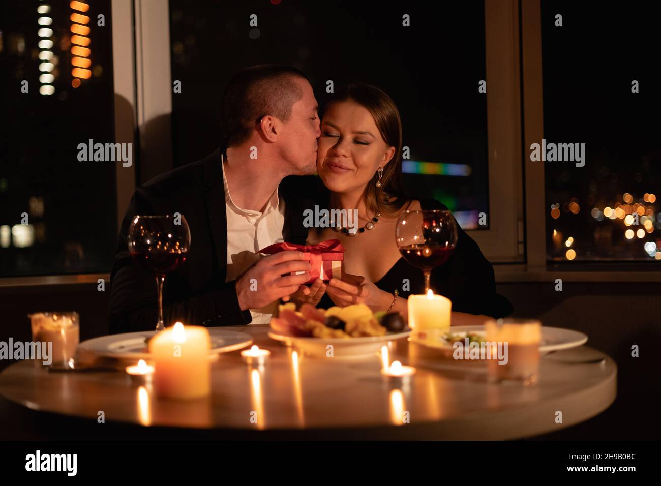 Romantic candlelight dinner for two, Valentine's Day date, authentic couple having dinner, a man ...