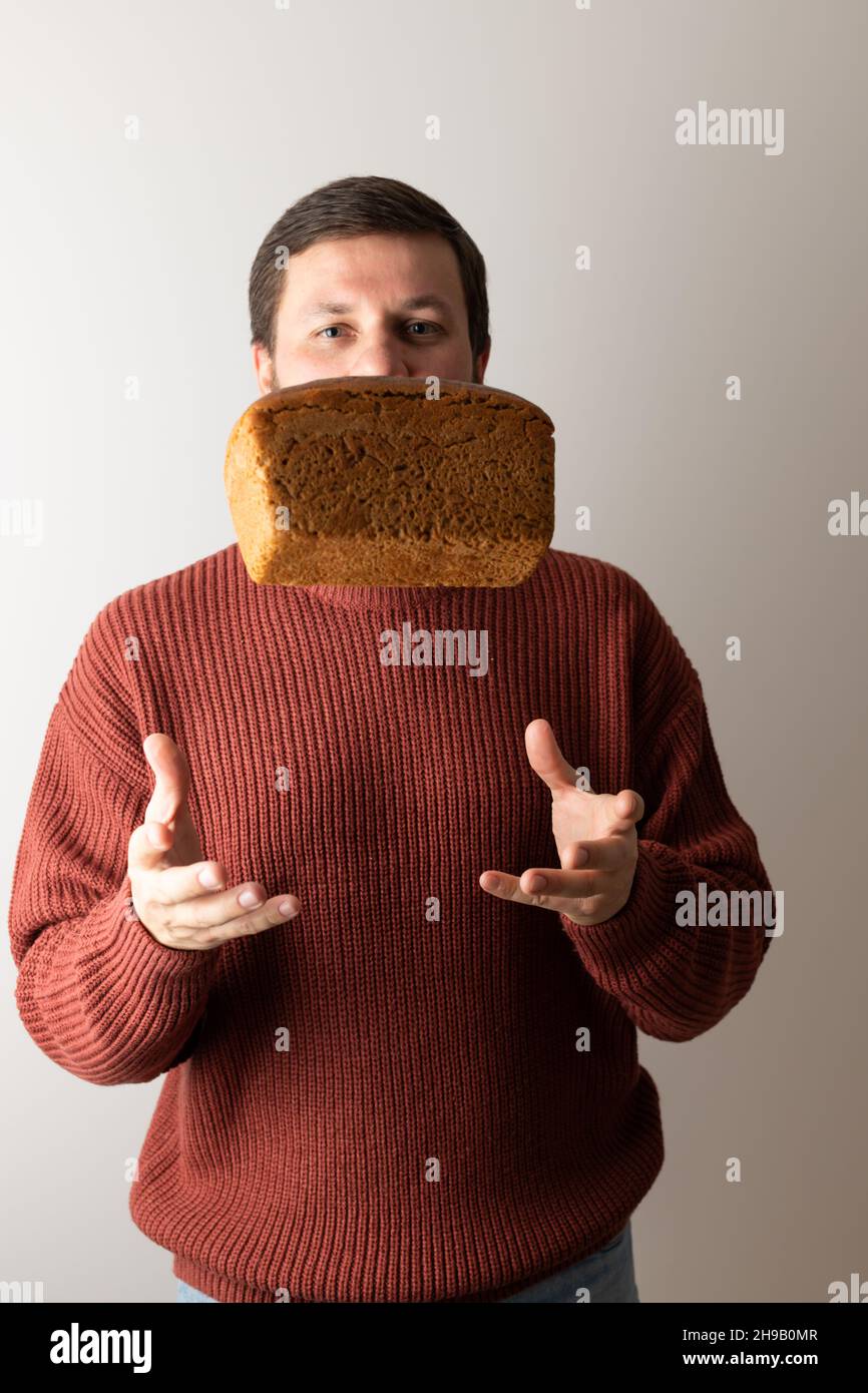 A man in a sweater throw up a loaf of rye bread into the air. Front ...