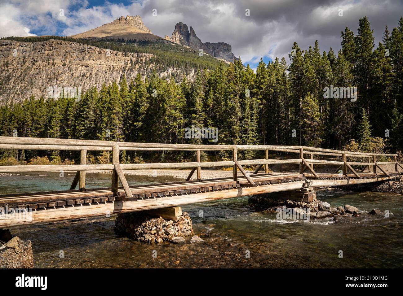 A wooden log bridge over a clear mountain creek in Banff National Park ...