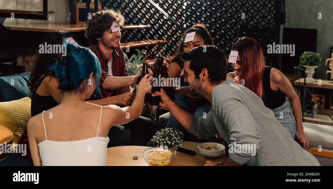Diverse group of young people partying and toasting a drink in the ...