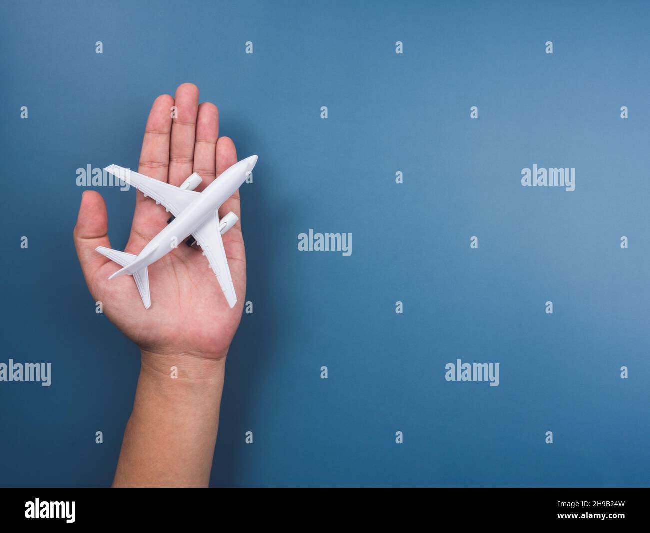 White plane toy model on hand on a blue background with copy space, top ...
