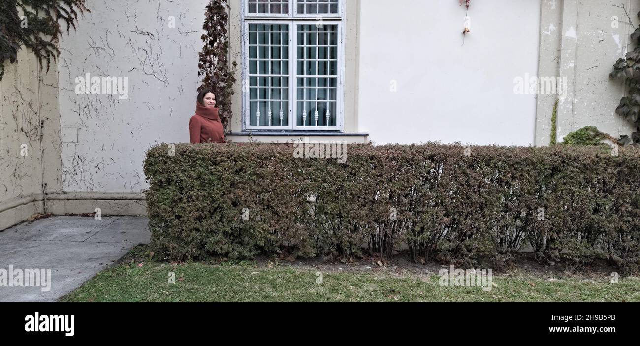 Austrian girl standing outside a building behind the bush Stock Photo ...