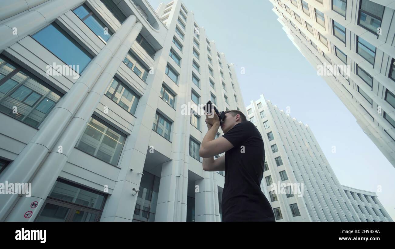 Young photographer takes picture of modern urban architecture. Action ...