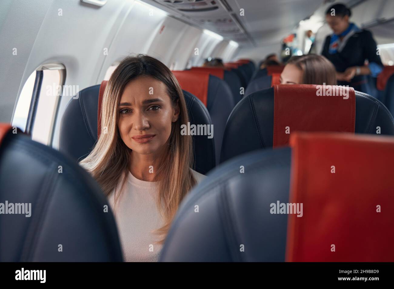Sad woman sitting on a plane near window Stock Photo - Alamy