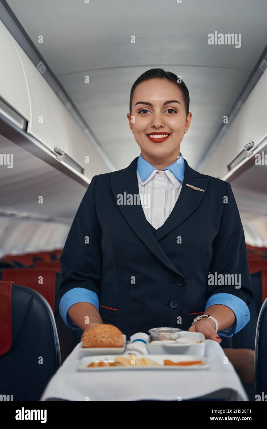 Welcoming stewardess pushing meal trolley inside plane Stock Photo - Alamy