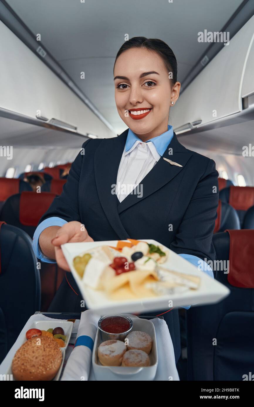 Happy flight hostess offering meal from catering trolley Stock Photo ...