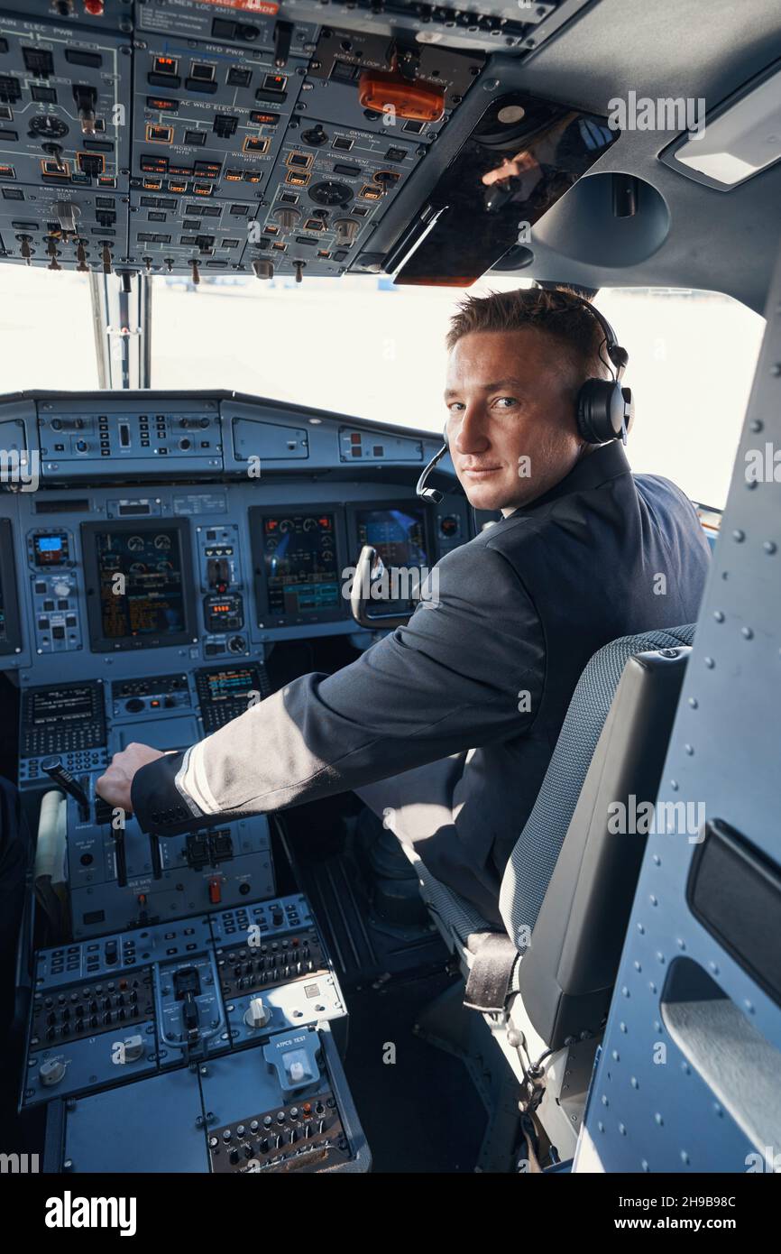 Caucasian first officer of airplane turning to camera while holding ...