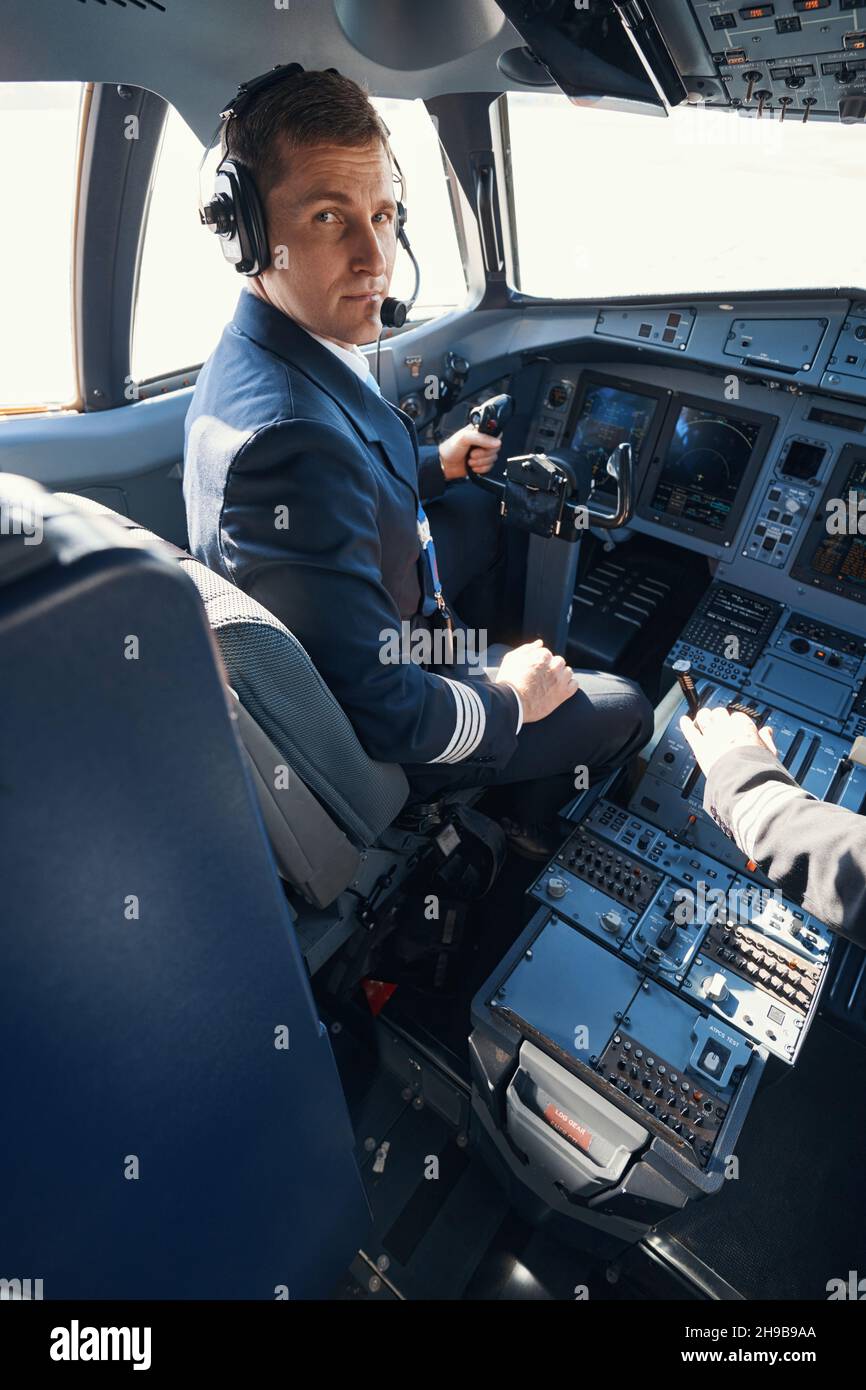 Caucasian pilot in command sitting in cockpit with headset on and ...