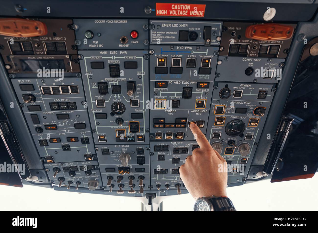Pilot of airplane reaching out to panel overhead and toggling switch ...