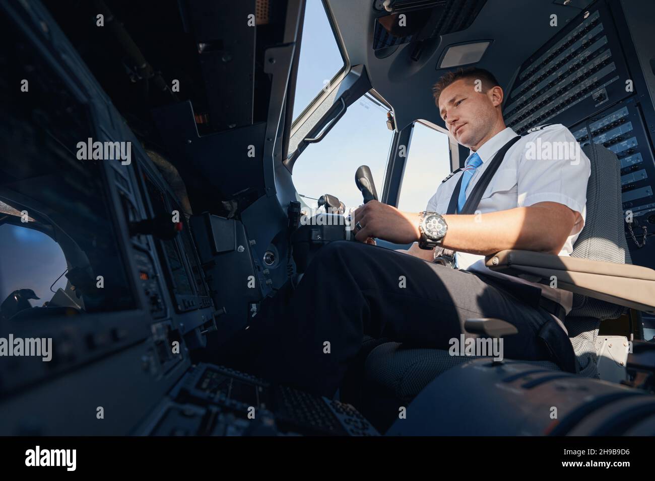 Side view of male co-pilot using control handle in cockpit for steering ...