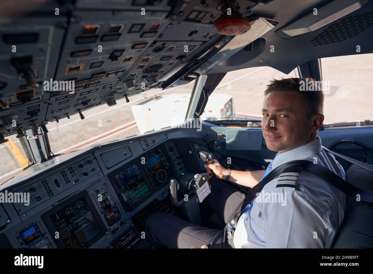 Co-pilot sitting in cockpit with fastened seatbelt and looking at ...
