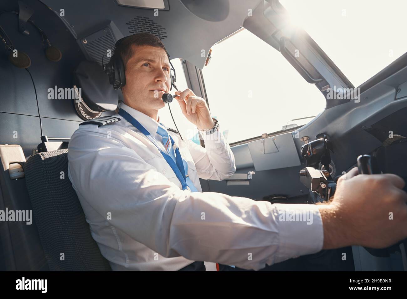 Caucasian pilot in white shirt talking in microphone of headset from ...
