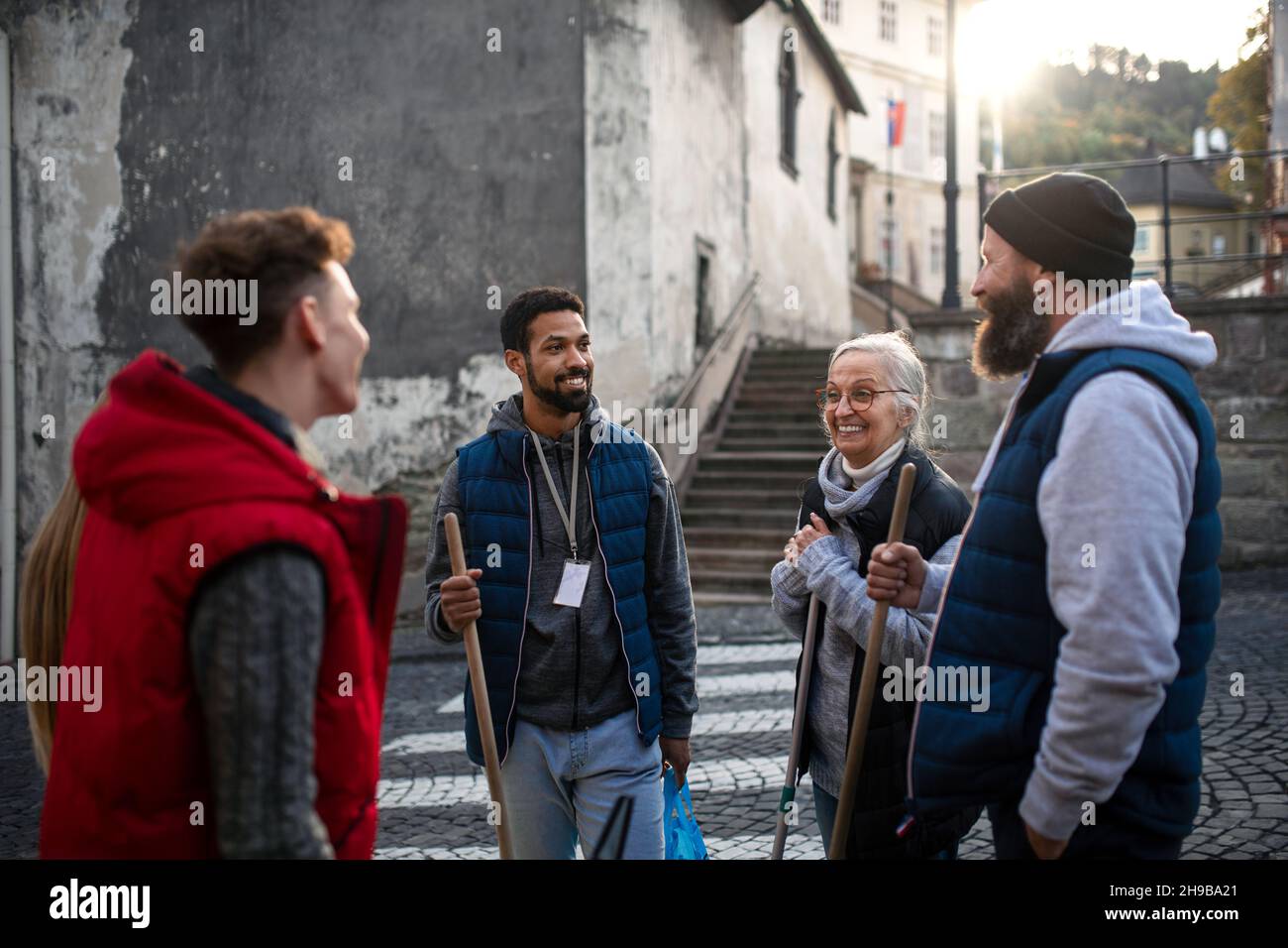 Group of happy volunteers talking and ready to clean up street ...