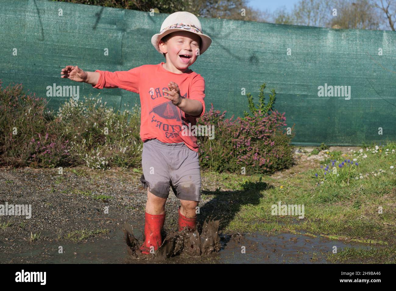 Happy male kid in rubber boots have fun playing in a puddle mud Stock ...