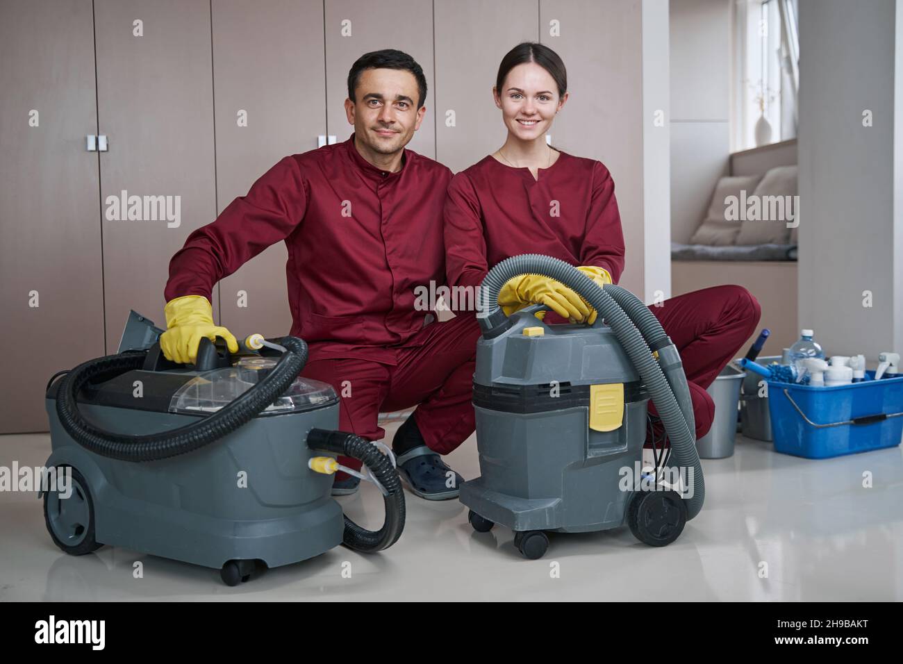 Cheerful cleaner and her colleague posing for camera before ...