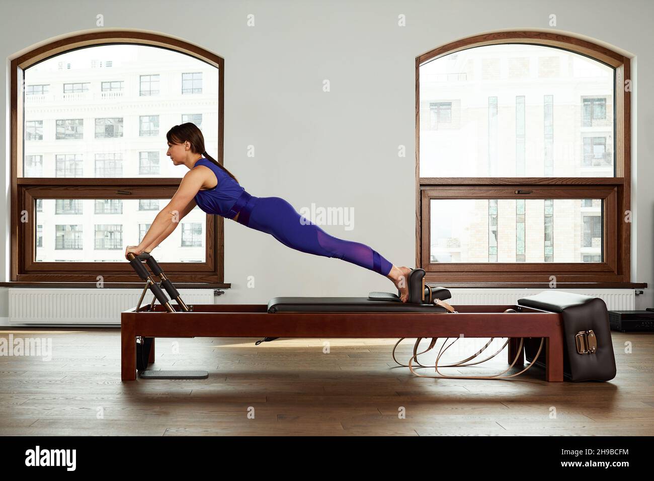 The instructor does exercises on the reformer, a beautiful girl trains ...