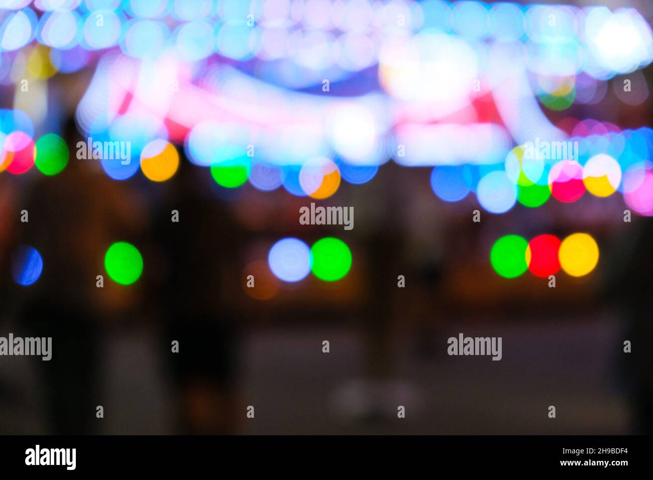 Defocused bright lights flash at a fun carnival at night. Amusement ...