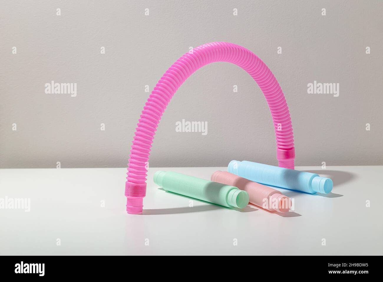 Blue mint and pink antistress pop tube toy lie under bright pink pipe ...