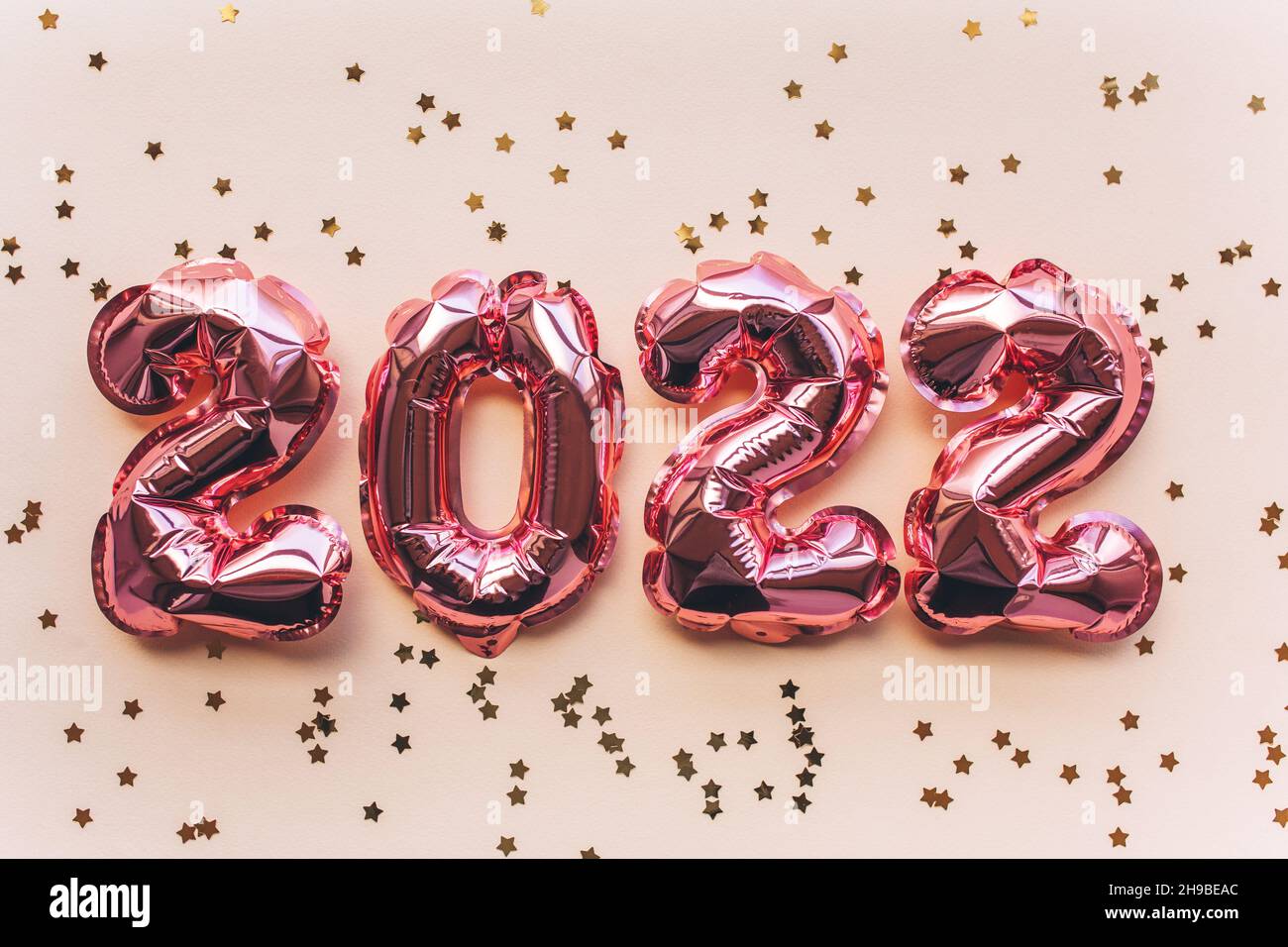 Balloons made of pink foil in the form of numbers 2022 with confetti on ...