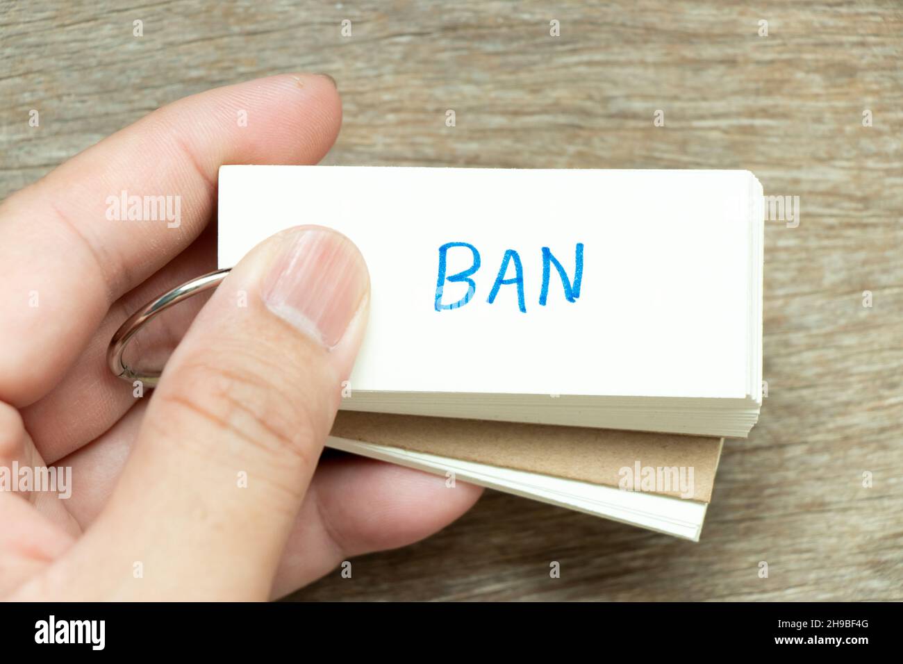 Man hold the flash card with handwriting word ban on wood background ...
