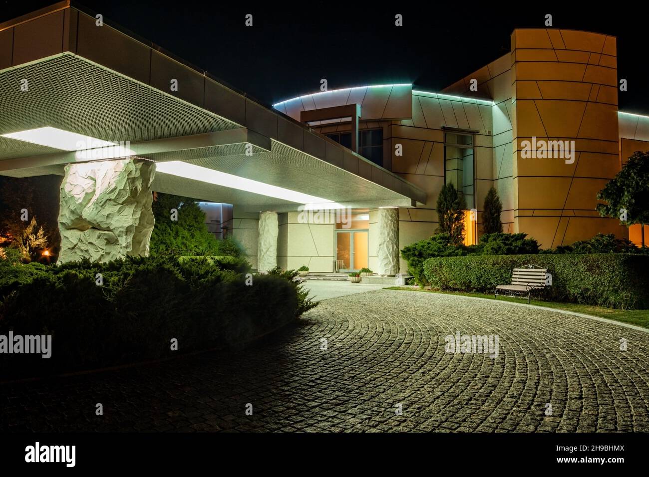 Night view of hotel main entrance with porch on rocky columns and paved ...