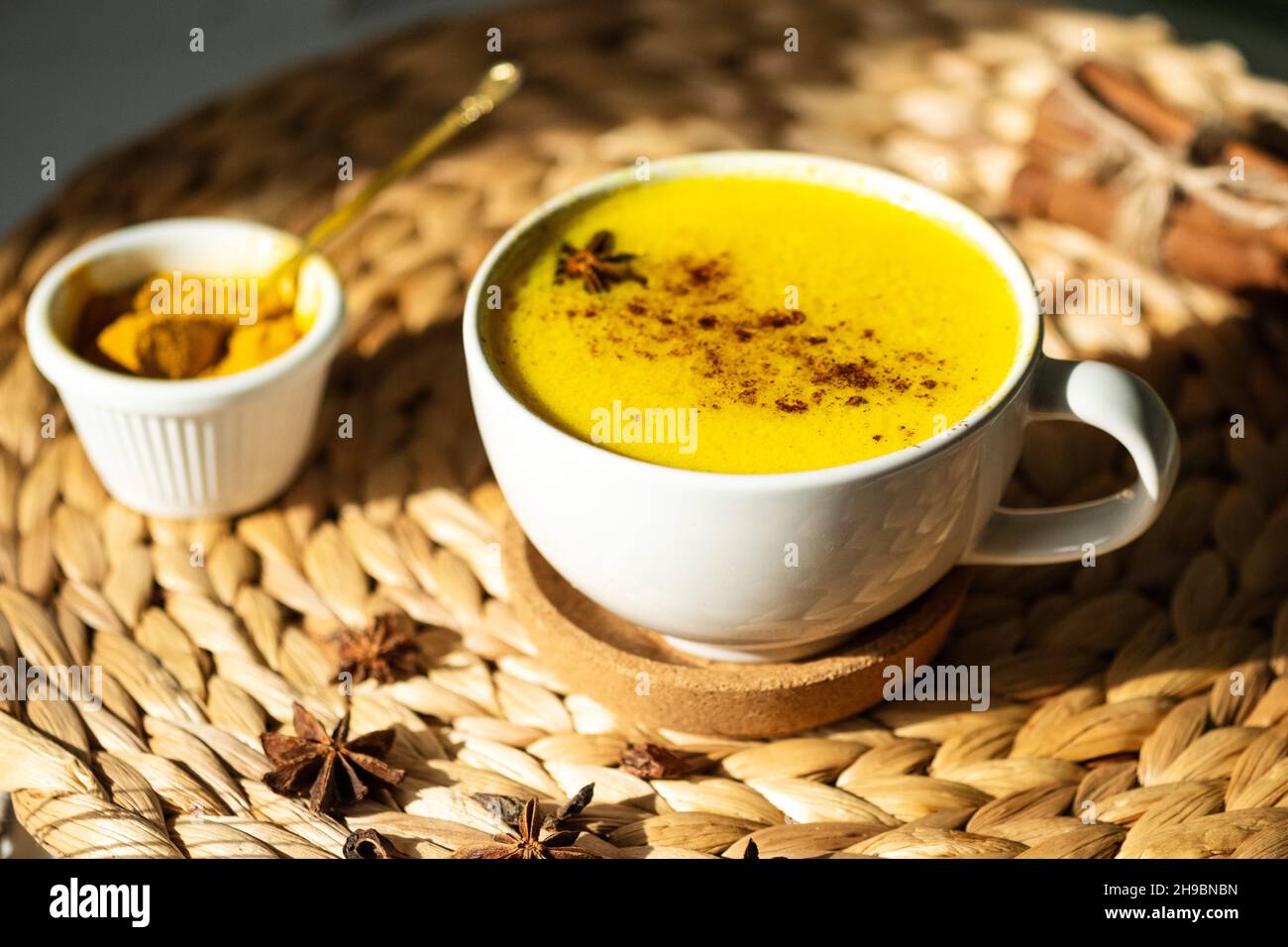 Top down view of Golden milk or Turmeric Latte cup on a straw plate ...