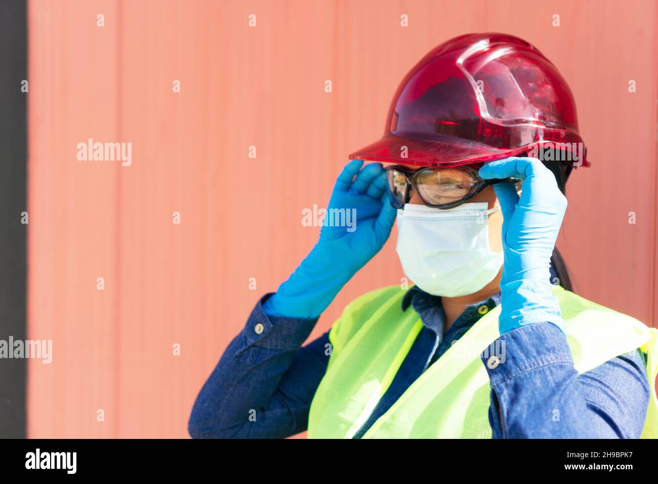 Industry worker wearing protective mask and putting on safety goggles ...
