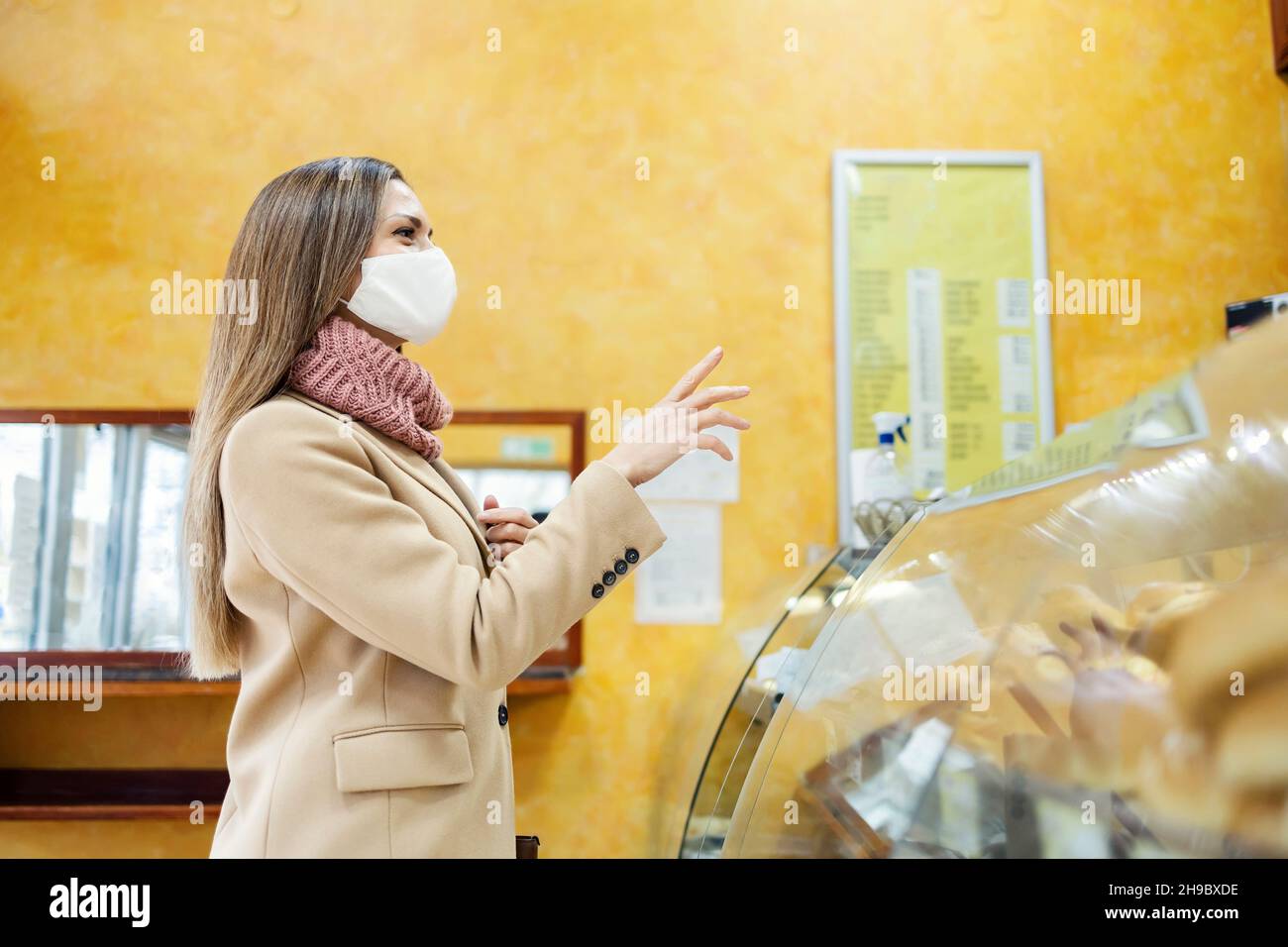 A customer standing in the bakery and choosing pastry. A woman in a ...