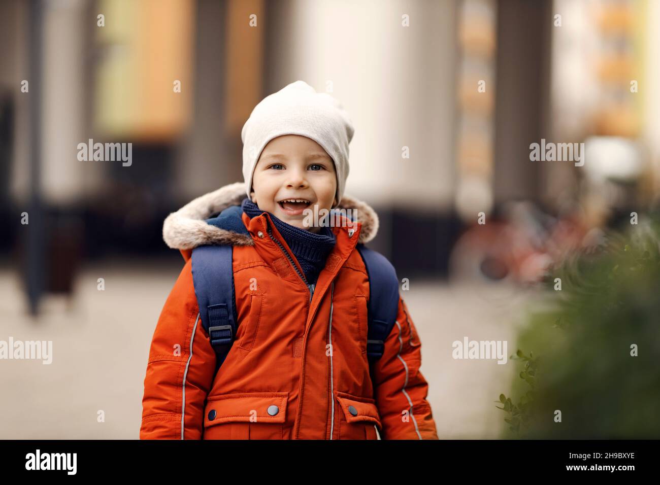 Happy kindergarten child with a backpack outdoors. A happy cute little ...