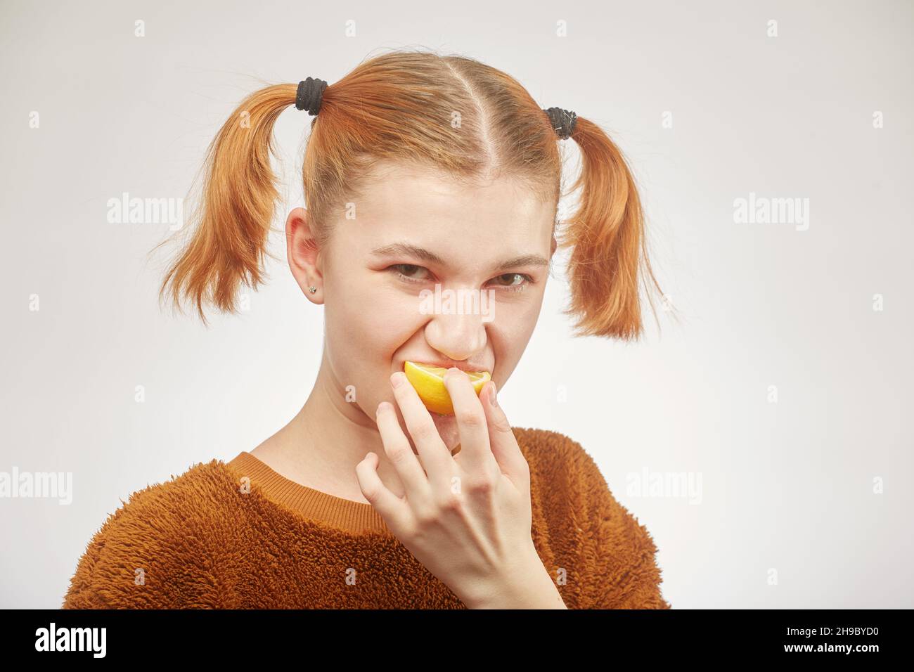 fun girl eats lemon on white background, grimacing Stock Photo - Alamy