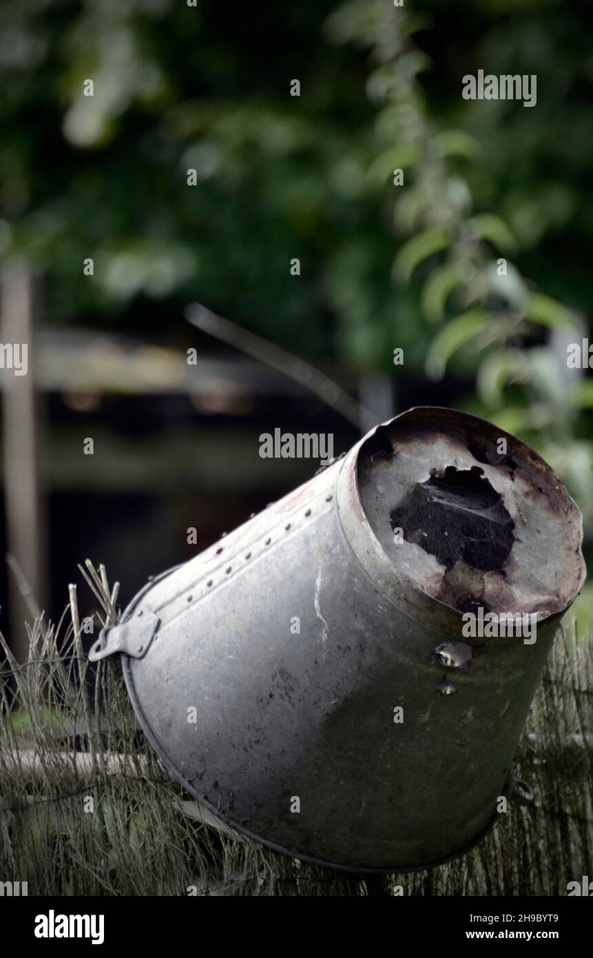 disgarded galvanised bucket with large rusty hole in bottom Stock Photo ...