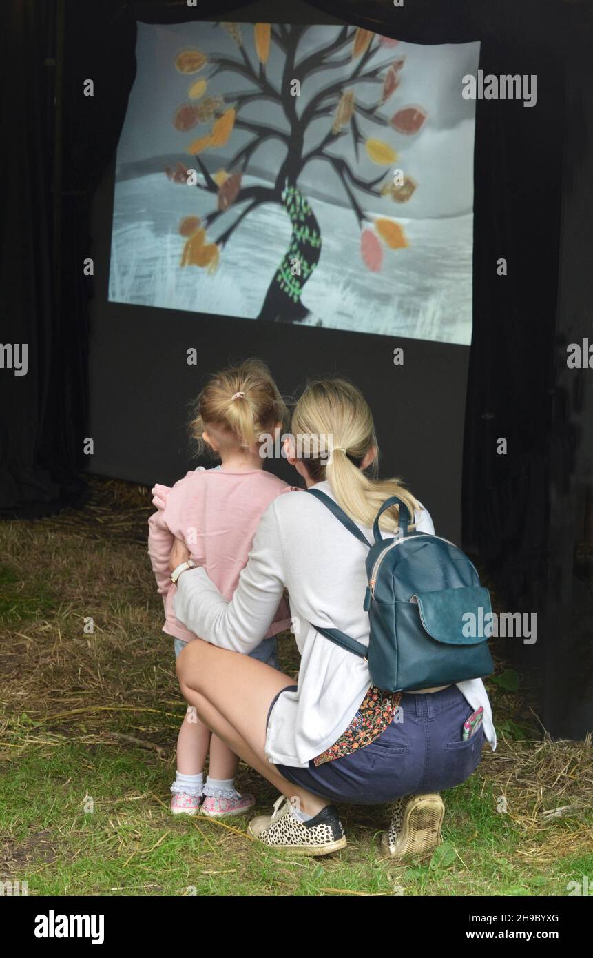 young mother with young child watching projected cartoon at rural ...
