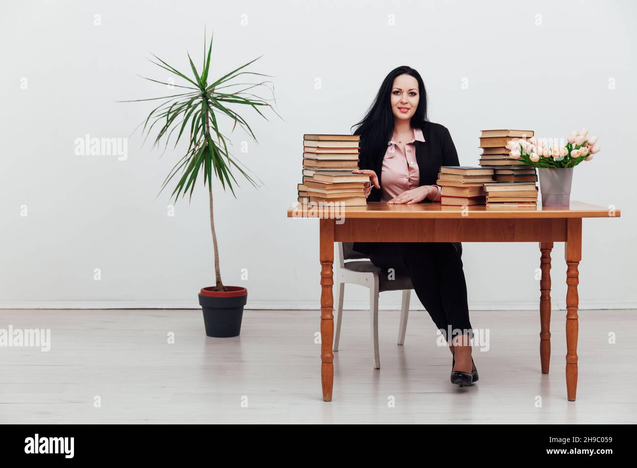 female teacher at a table with books for teaching Stock Photo - Alamy
