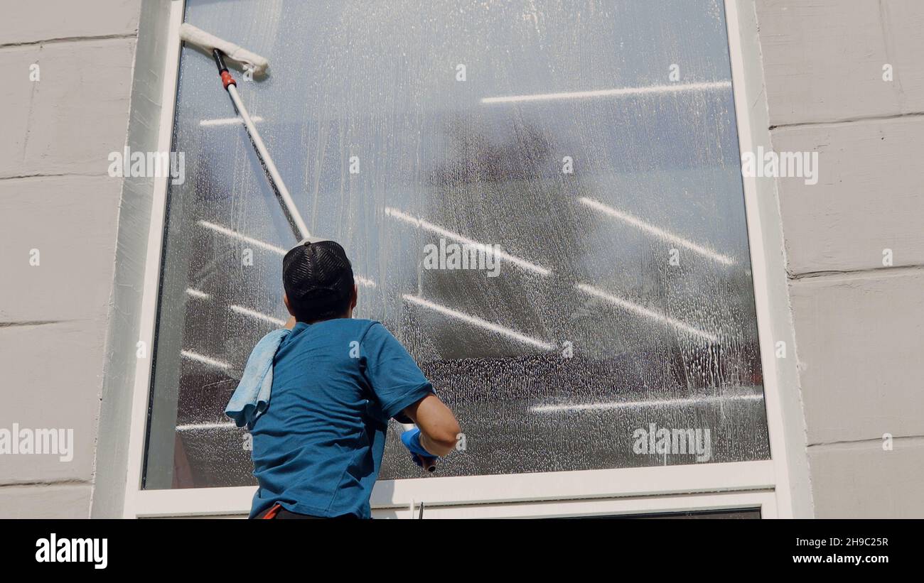 Male professional cleaning service worker in overalls cleans the ...