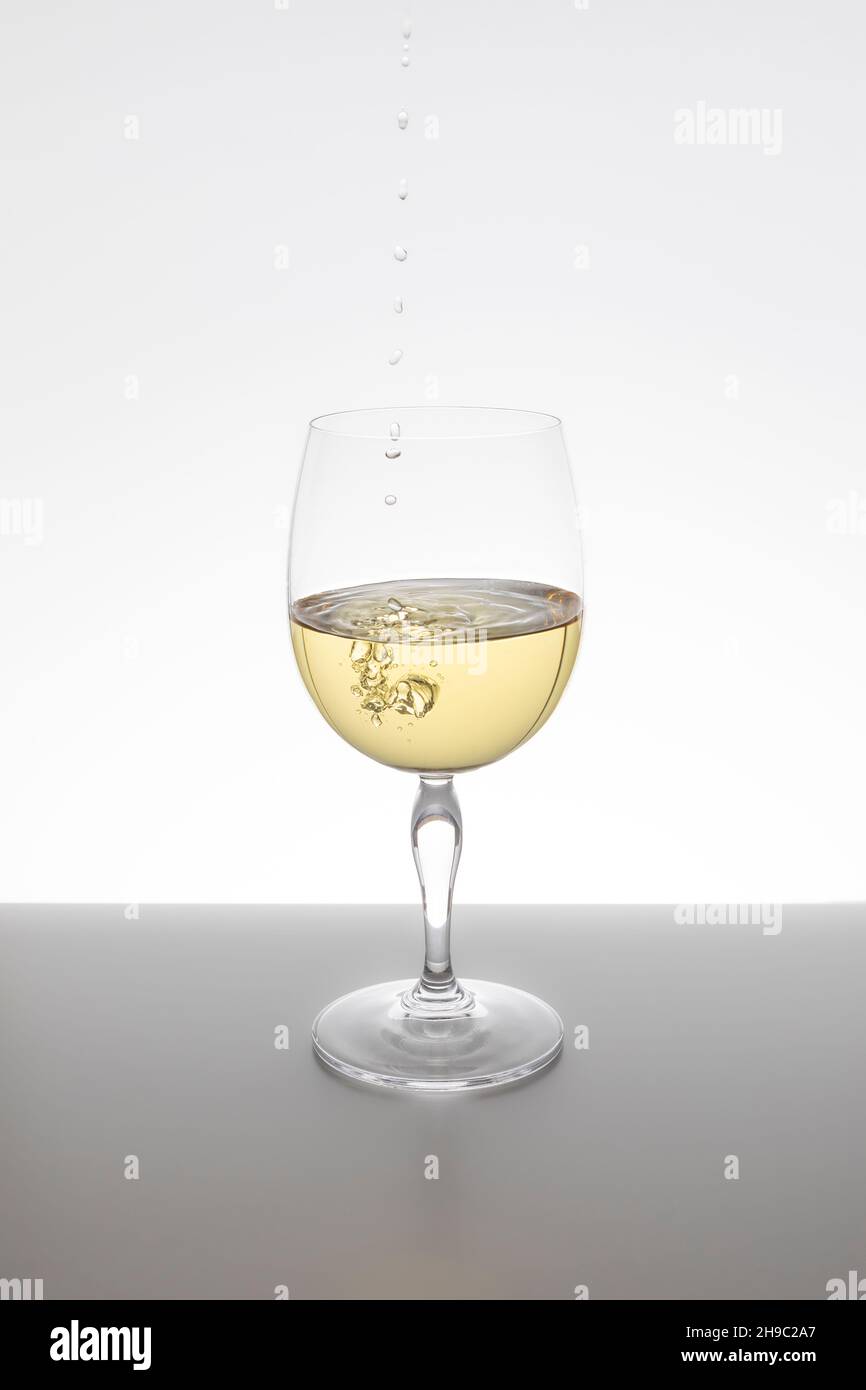 white wine falling in glass on white background Stock Photo - Alamy