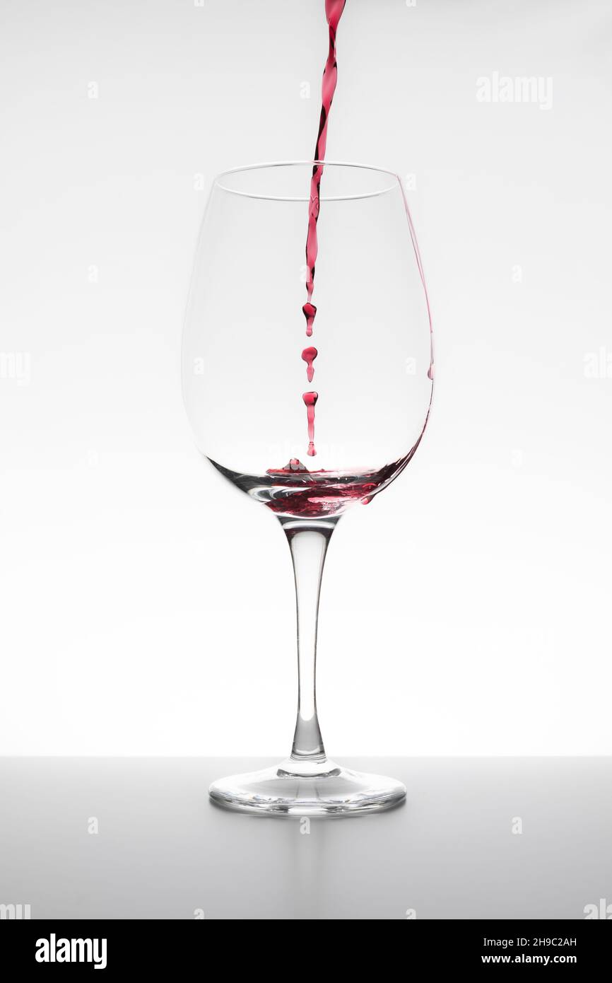 Red wine falling in glass on white background Stock Photo - Alamy