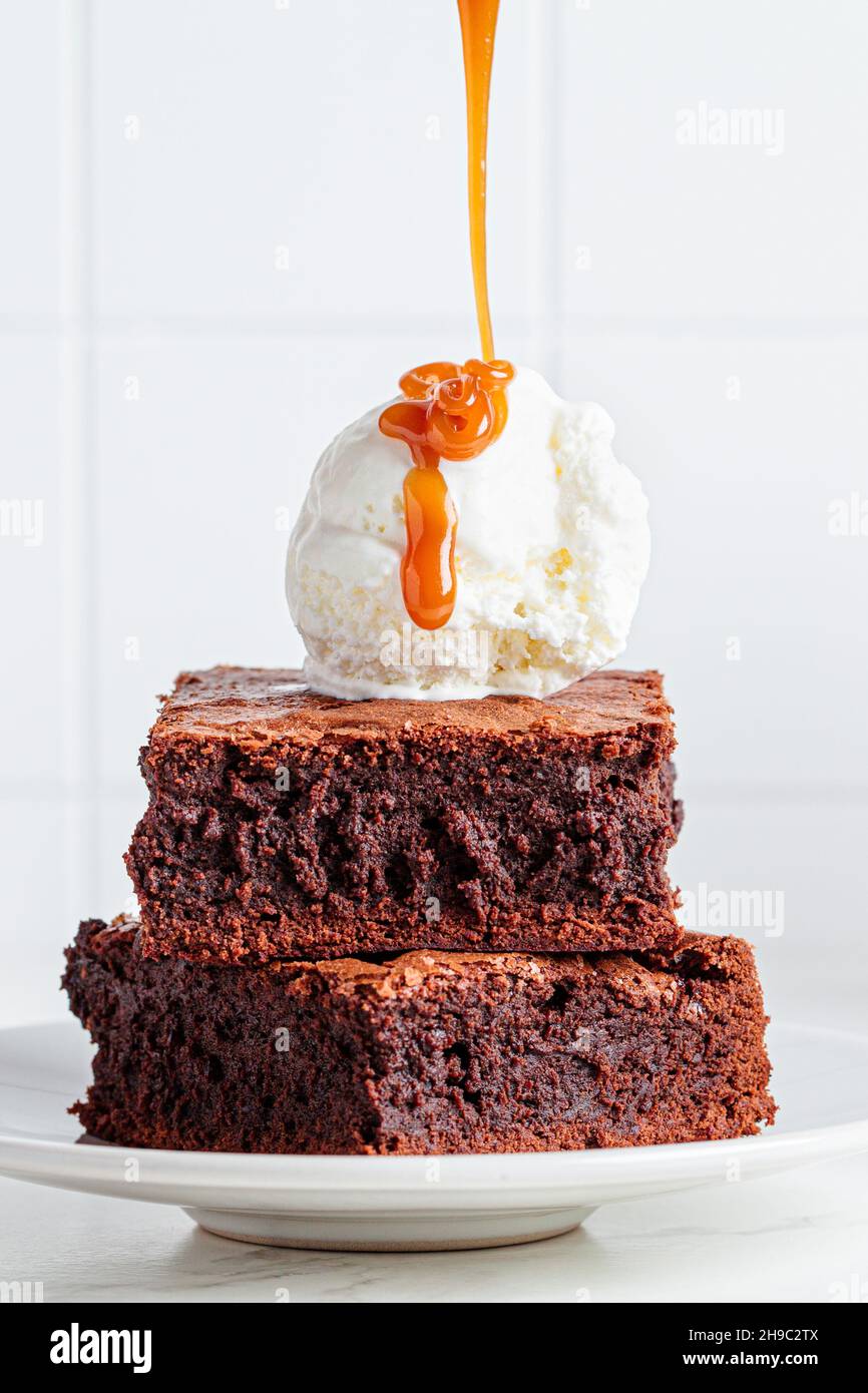 Stack of brownie squares with a scoop of ice cream and caramel, white ...
