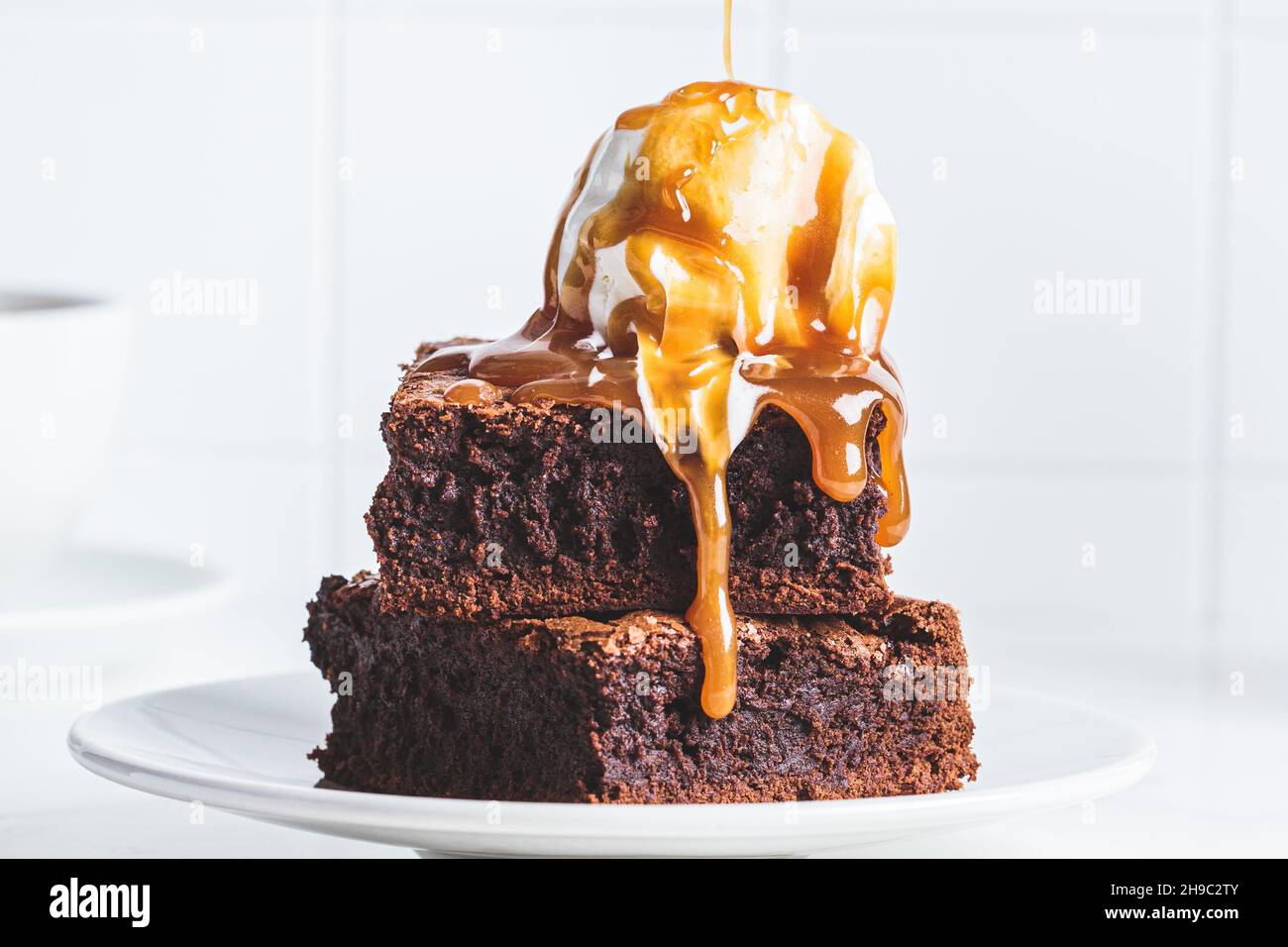 Stack of brownie squares with a scoop of ice cream and caramel, white ...