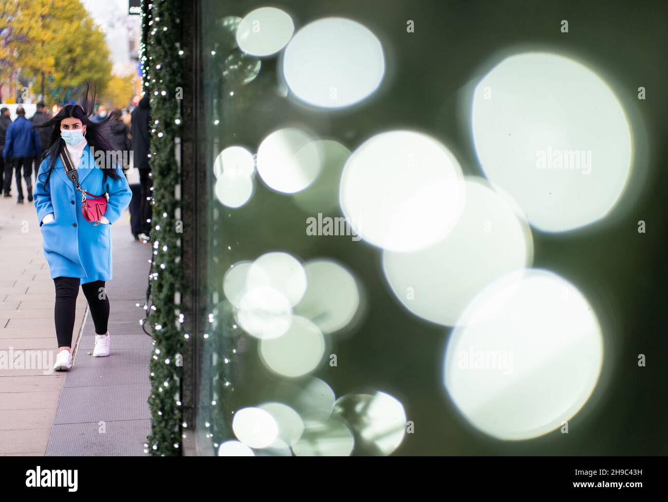 A shopper wearing a face mask passes Christmas decorations outside a ...