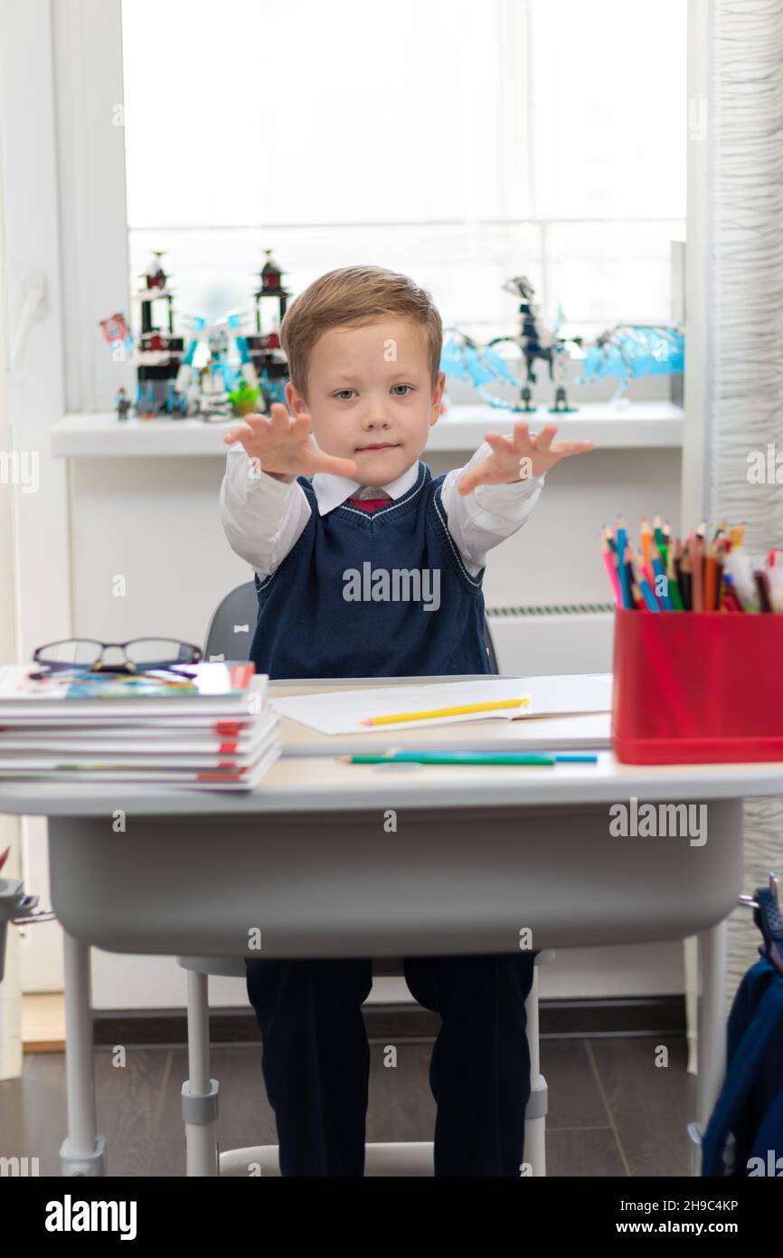 Cute boy first grader in school uniform at home during a break fooling ...