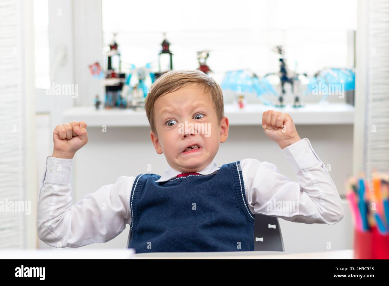 Cute boy first grader in school uniform at home during a break fooling ...