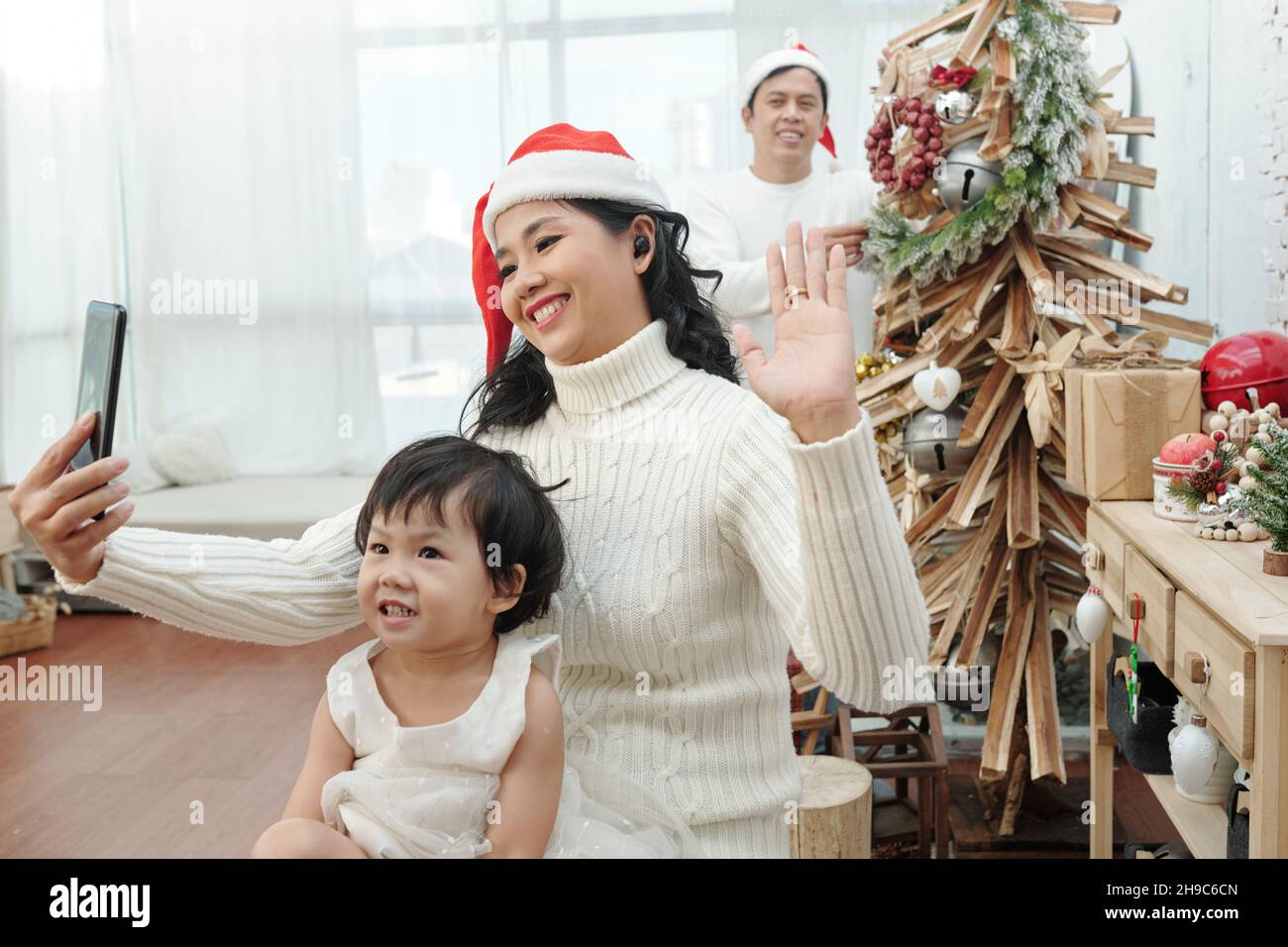 Pretty woman and her little daughter video calling family members to ...