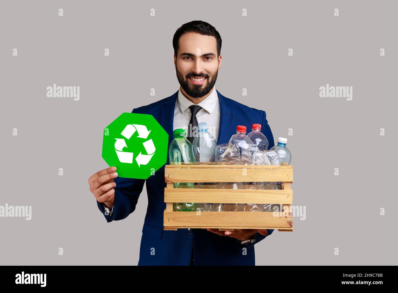 Bearded man holding box with plastic bottles and recycling green symbol ...