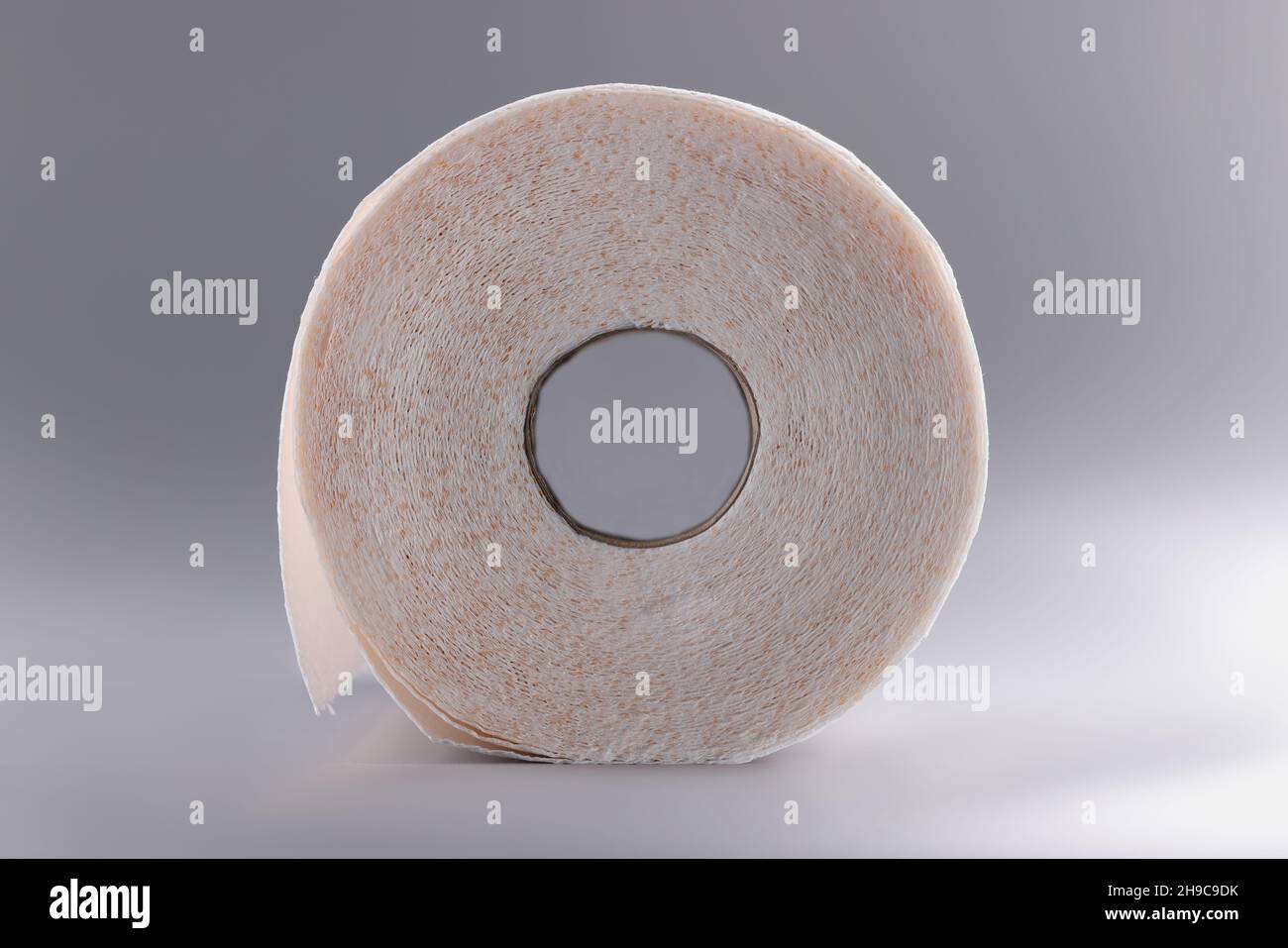 Roll of toilet paper lying on gray background closeup Stock Photo - Alamy